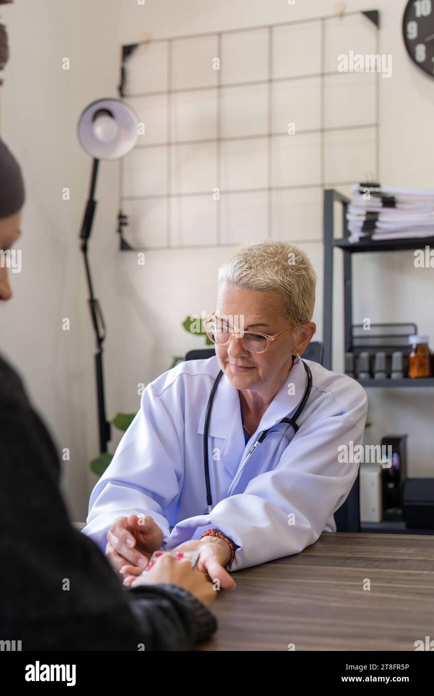 Senior woman doctor and female patient talking recommend pill medical ...