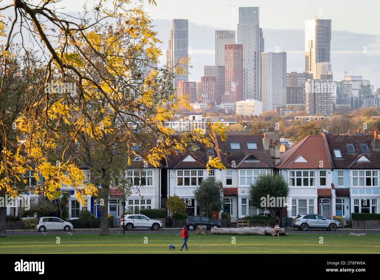 A dog walker passes in front of residential London homes in the ...