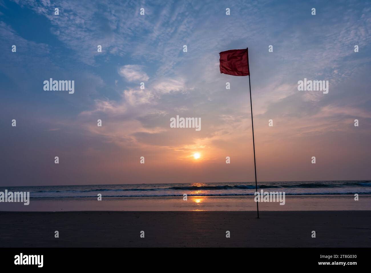 red flag on beach on sea or ocean at sunset as symbol of danger. The ...