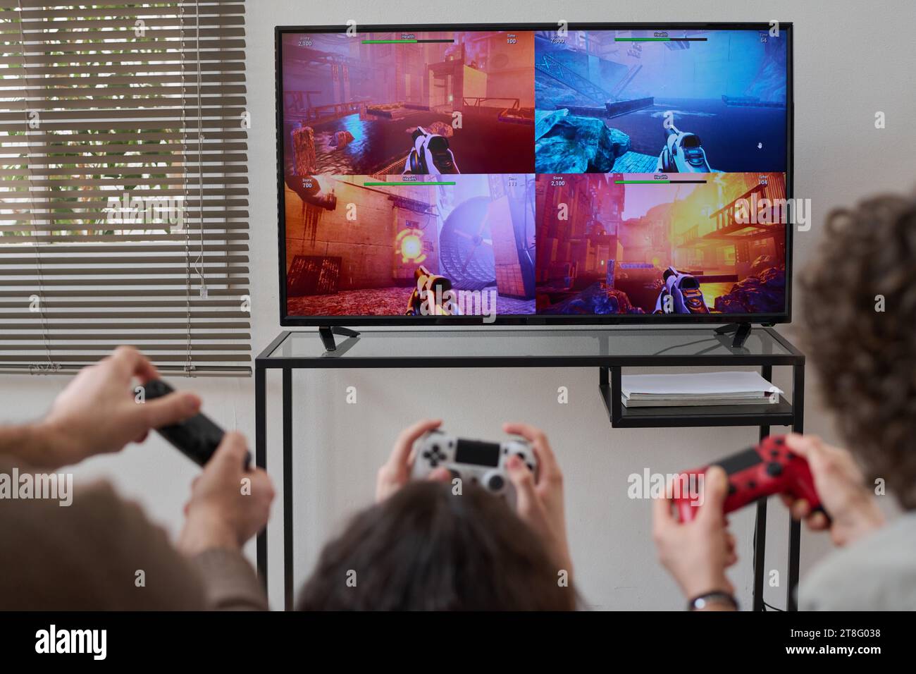 Rear view of family of three using joysticks to play video game on TV ...