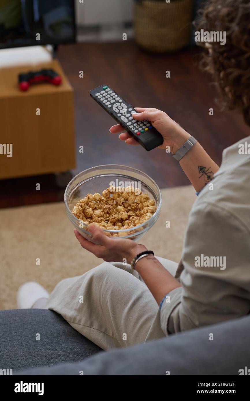 Vertical image of woman watching TV with popcorn at home Stock Photo ...