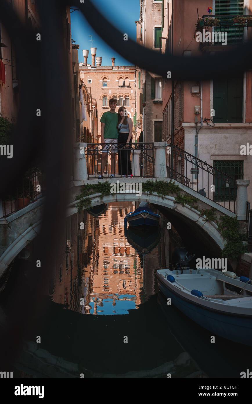 Romantic couple standing on bridge in Venice, Italy, looking out over ...