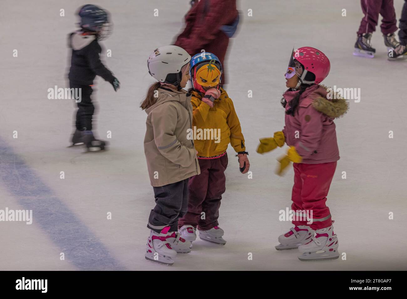 Beautiful view of happy children in carnival masks stand on ice rink at ...