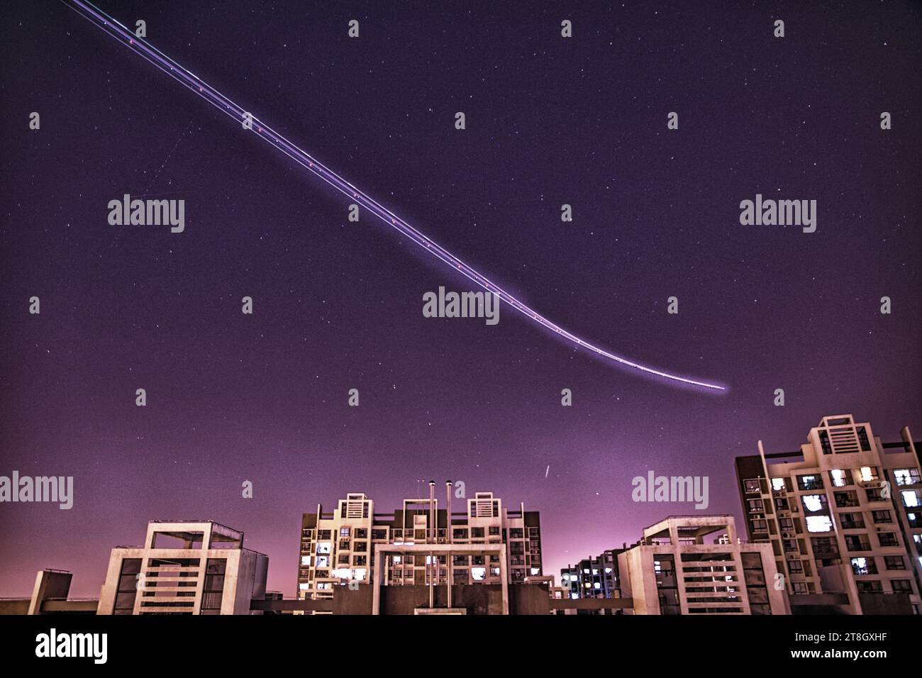A modern jet aircraft is seen soaring above the city skyline at dusk ...