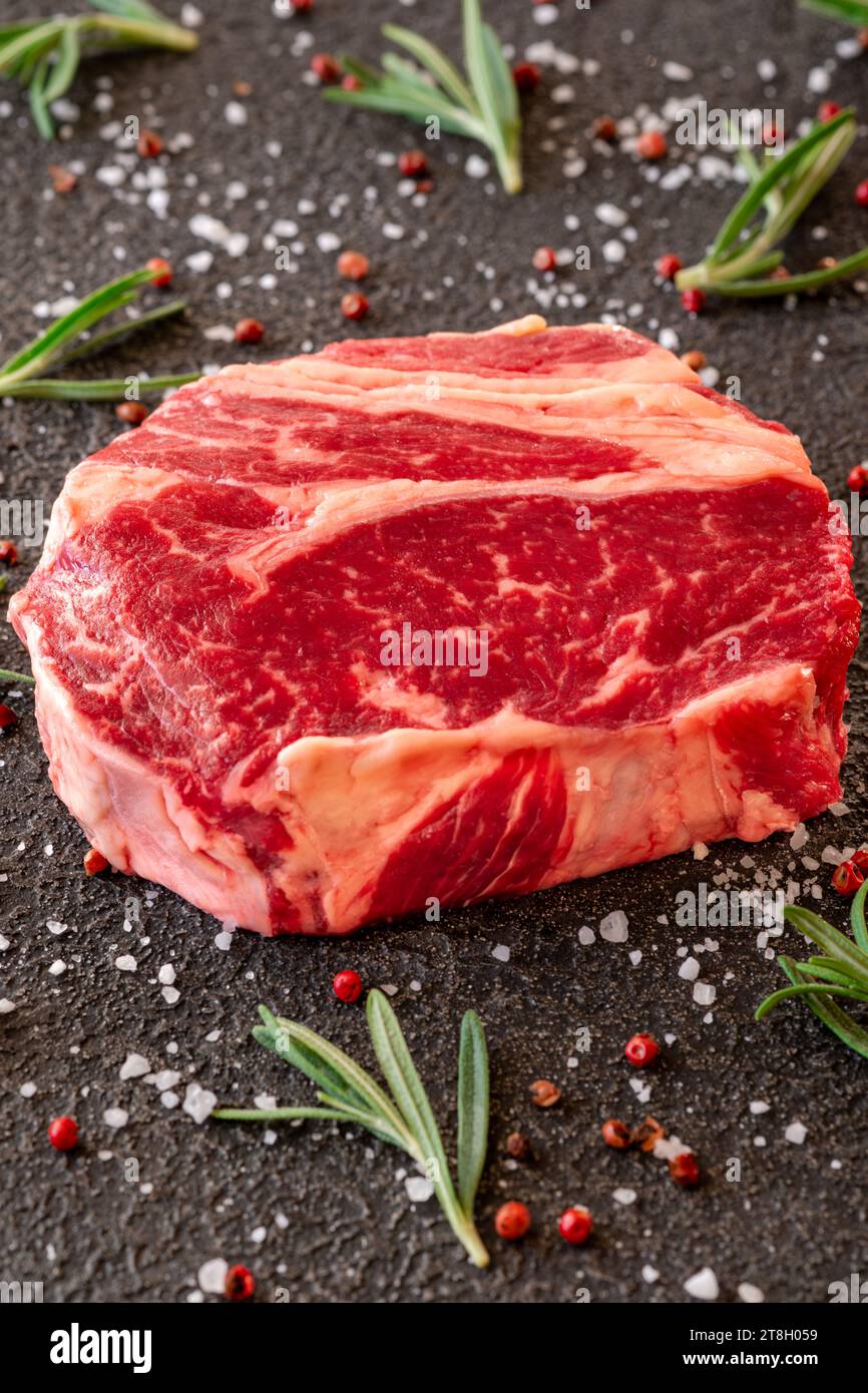 Uncooked rib eye beef steak on the black background Stock Photo - Alamy