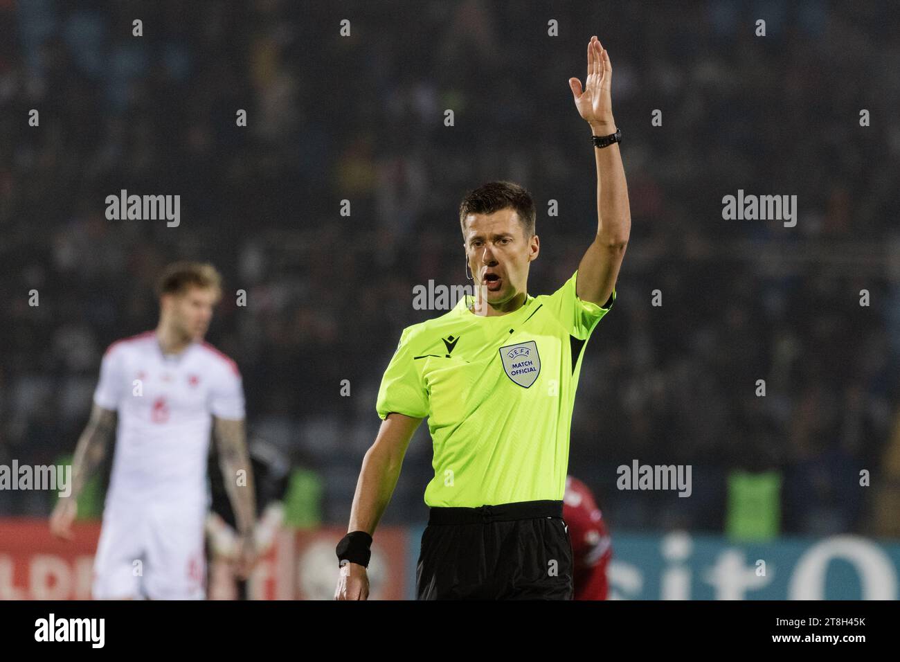 An experienced referee wearing a bright yellow uniform stands with ...