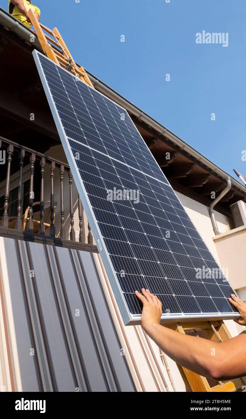 worker lifting solar panel up ladder to rooftop. Navarre, Spain, Europe ...