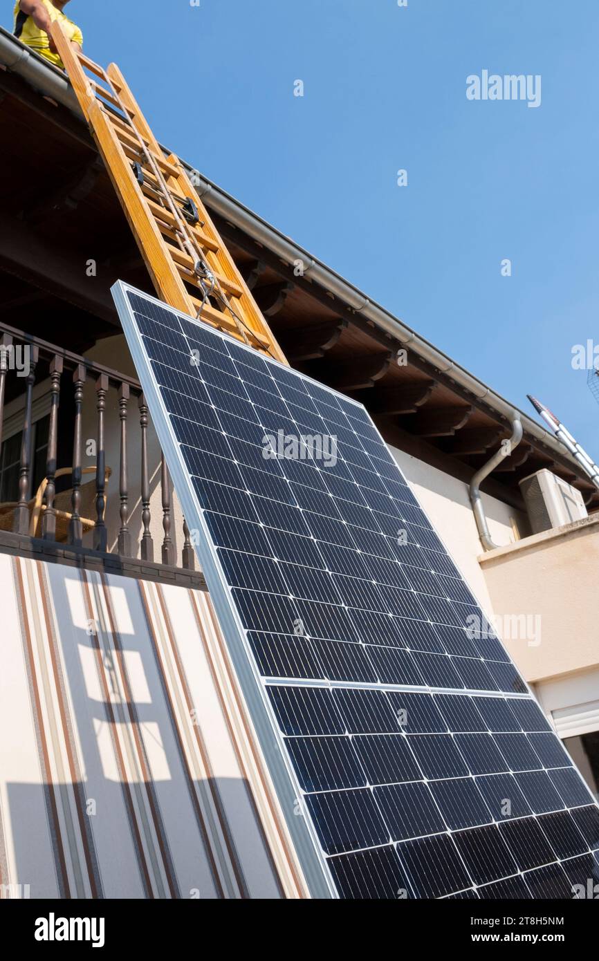worker lifting solar panel up ladder to rooftop. Navarre, Spain, Europe ...
