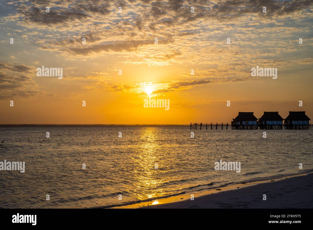 Horizontal photo of Sunset reflecting in the sea with jetty and huts in ...