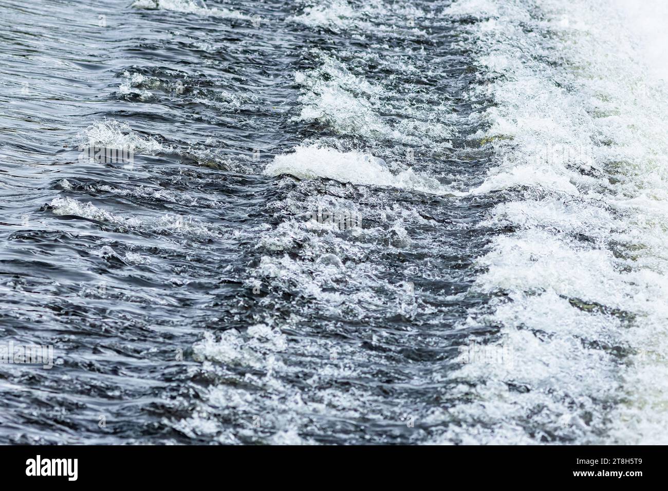 View of shallow water flowing over the weir making lengthways waves ...