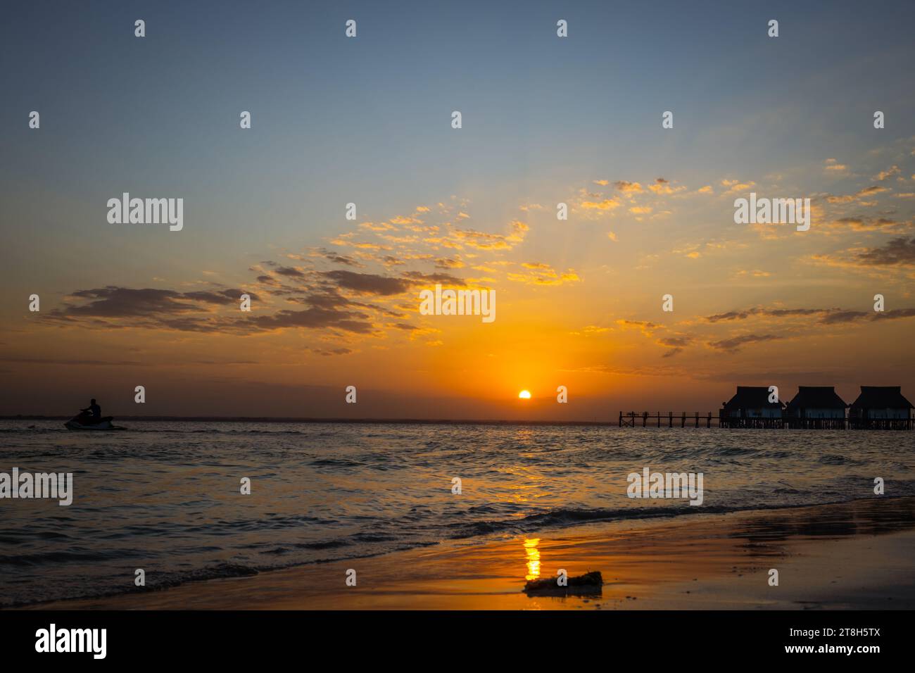 Horizontal photo of Sunset reflecting in the sea with jetty and huts in ...