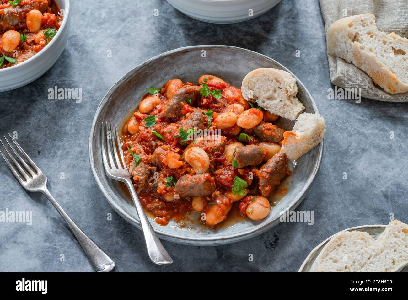 Beef chipolatas and bean casserole with crusty bread Stock Photo - Alamy