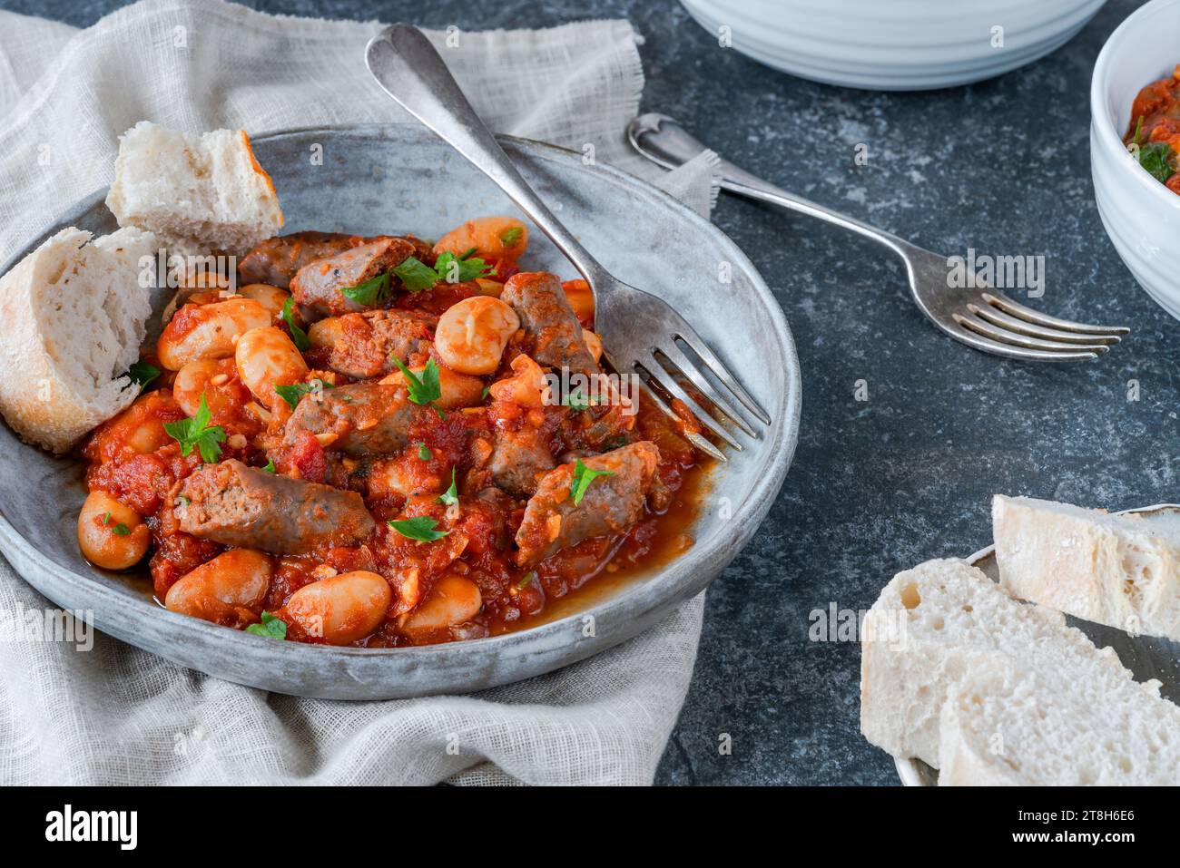 Beef chipolatas and bean casserole with crusty bread Stock Photo - Alamy