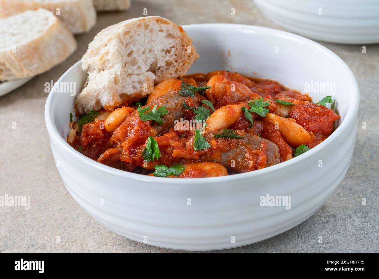 Beef chipolatas and bean casserole with crusty bread Stock Photo - Alamy