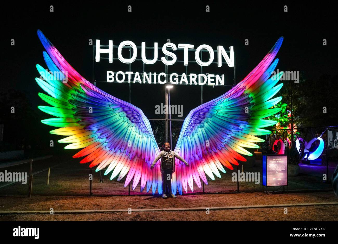 A girl stands in front of giant rainbow wings during the new holiday ...