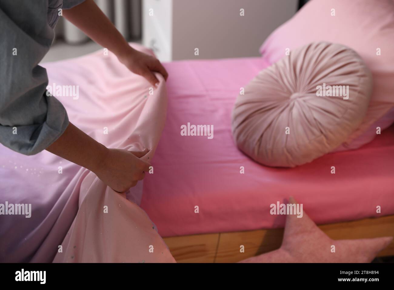 Woman making bed with new linens in children's room, closeup. Modern ...