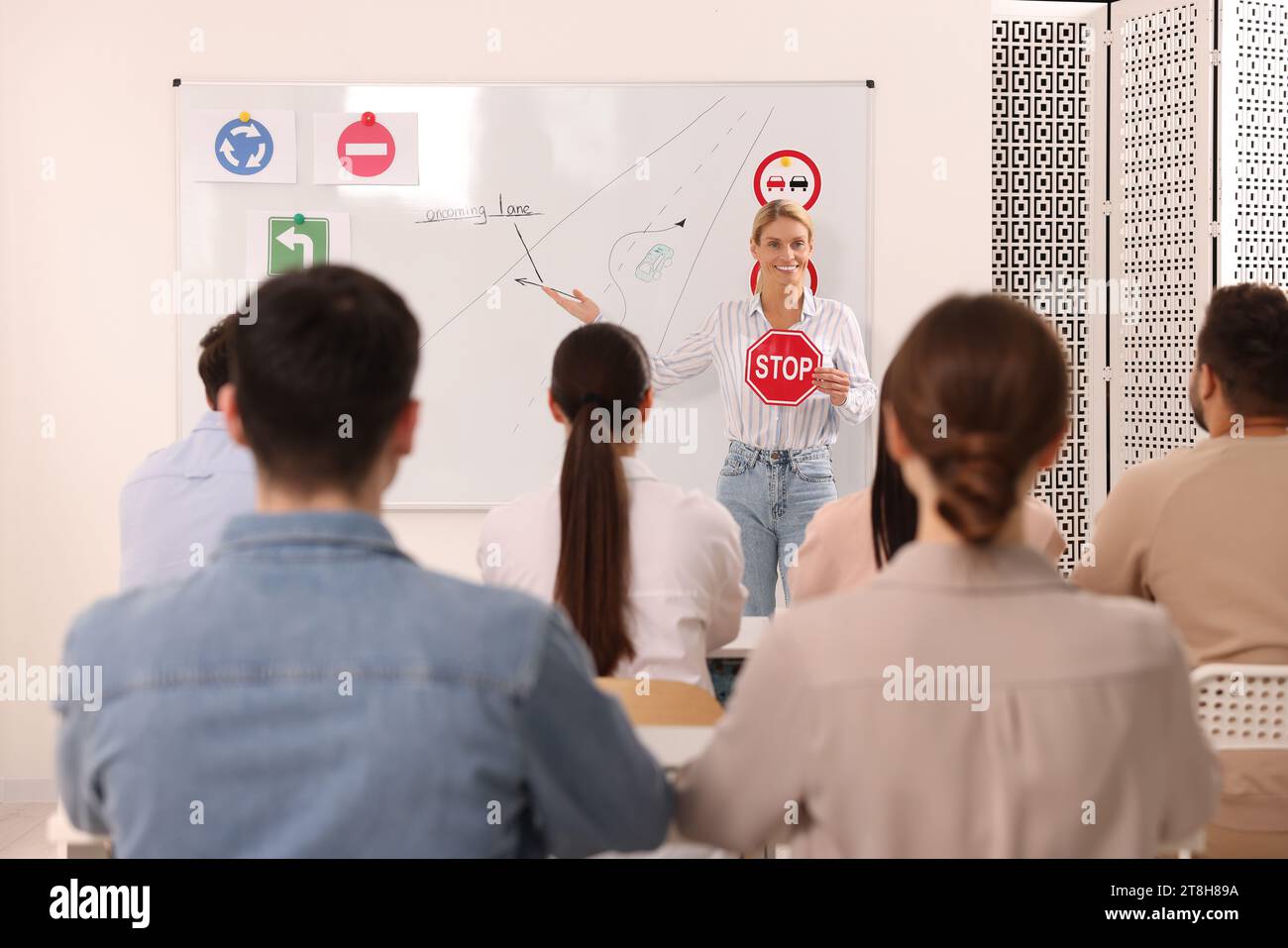 Teacher showing Stop road sign near whiteboard during lesson in driving ...