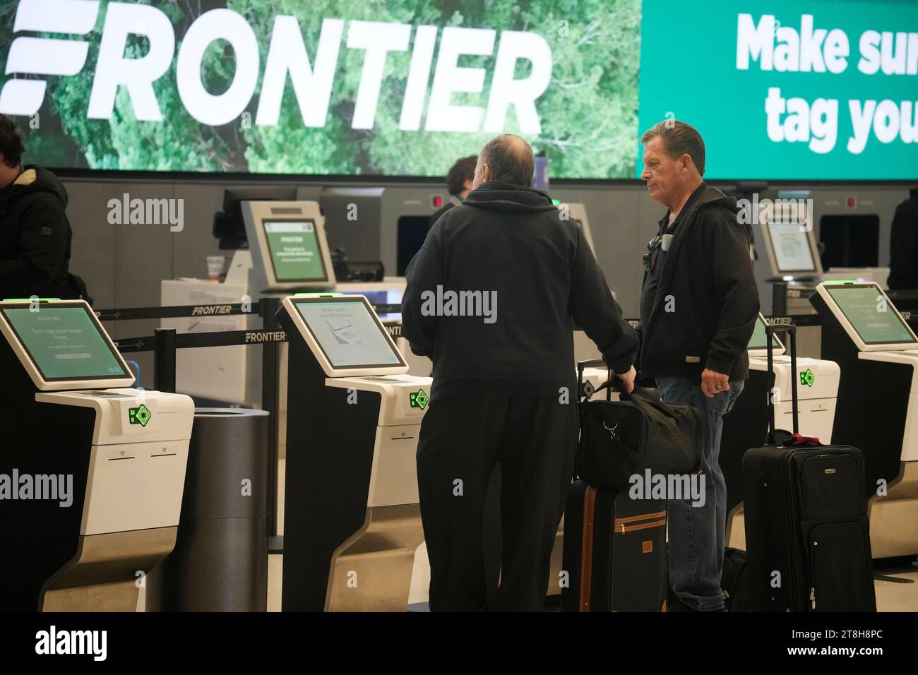 Travelers check in at the self-service ticketing kiosks for Frontier ...
