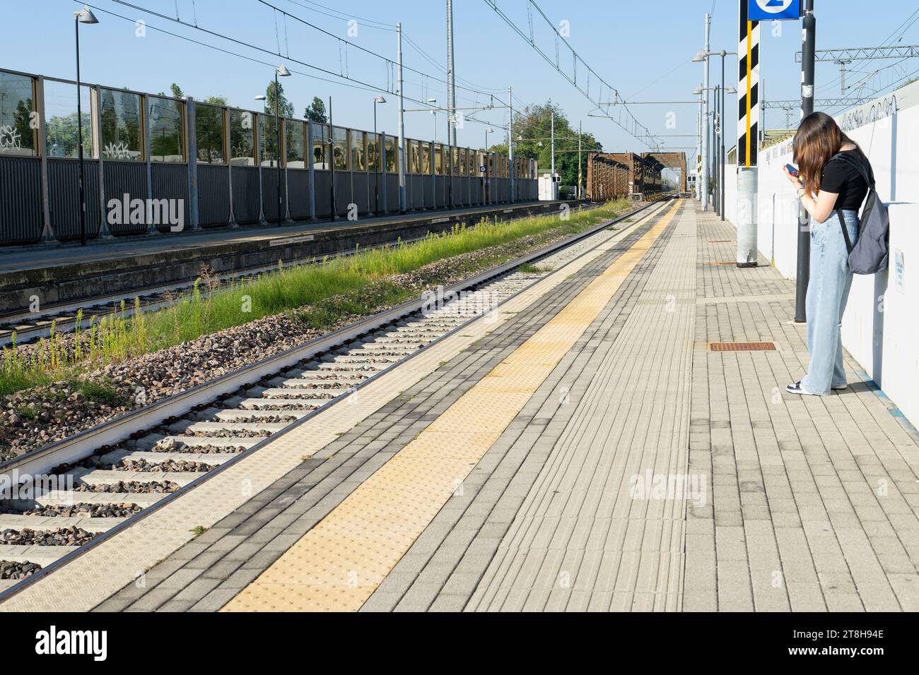 A young girl waits for the train to arrive at the outdoor stop while ...