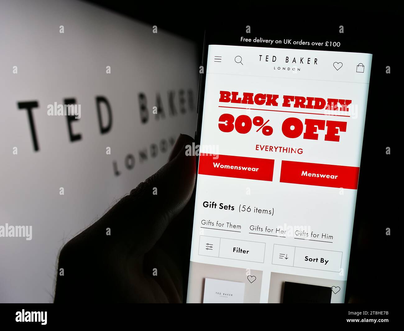 Person holding cellphone with webpage of British clothing retail company Ted Baker plc in front ...