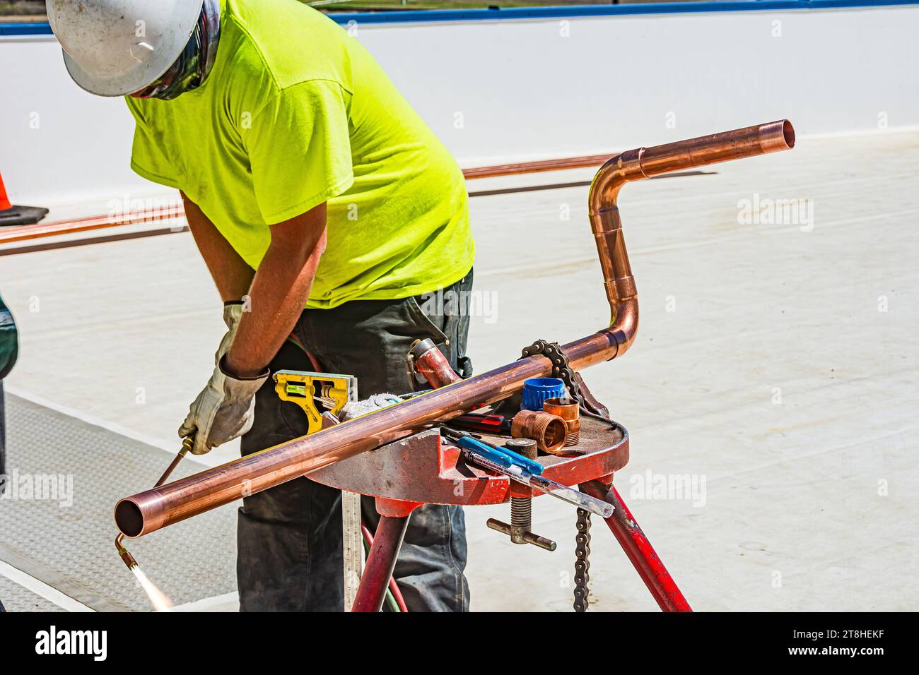 Construction worker preparing to braze an elbow on a length of copper ...