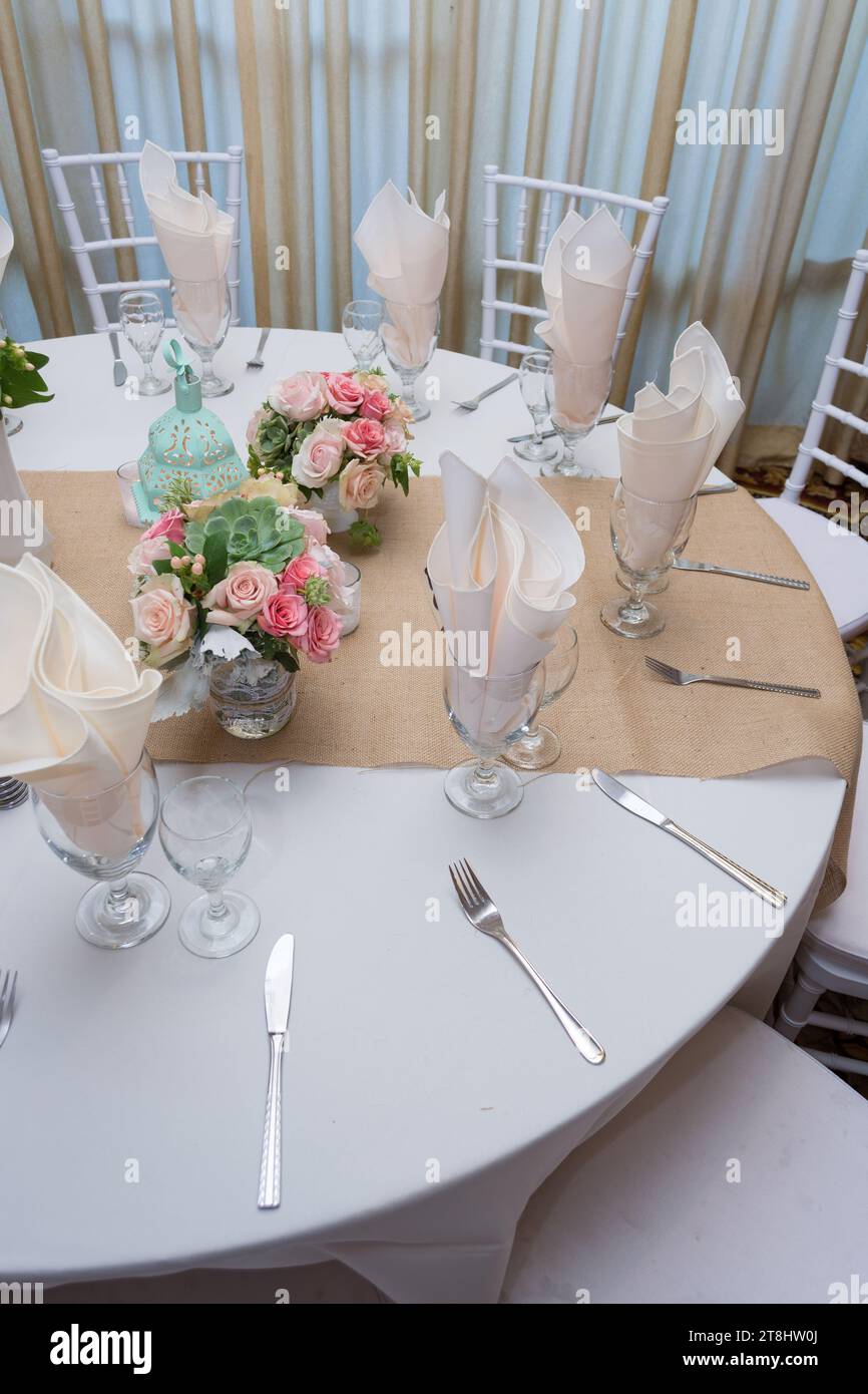 A round table is adorned with a vibrant display of fresh pink roses and ...
