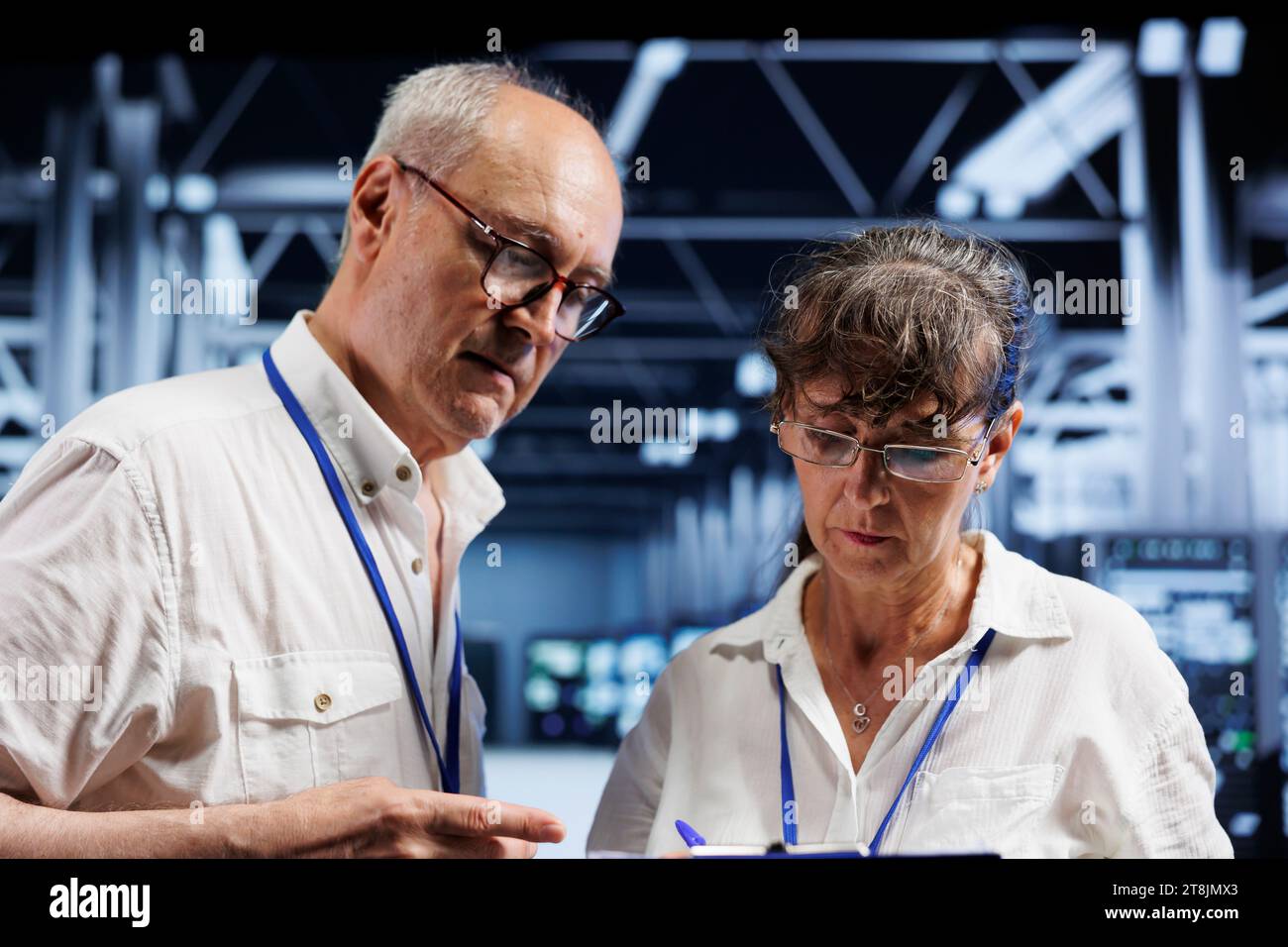 Elderly IT coworking programmers in high tech workspace using laptop to ...