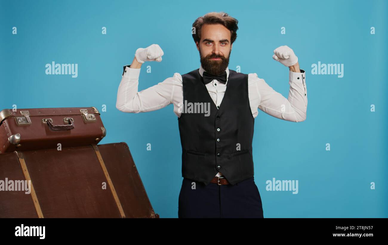 Modern bellboy flexing muscles in studio, showing off strength ...