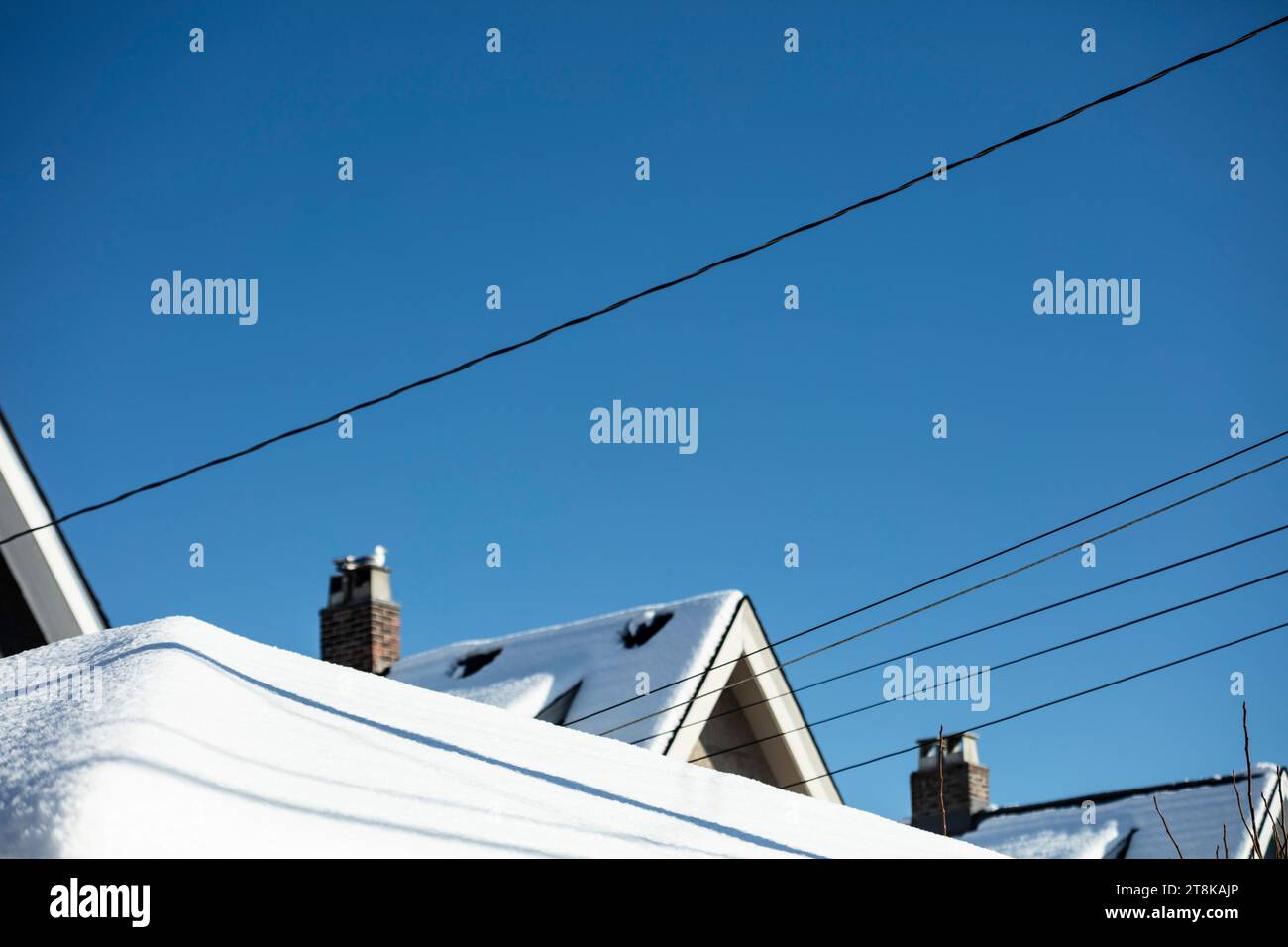 Snow-covered roofs and electrical wires against blue sky Stock Photo ...