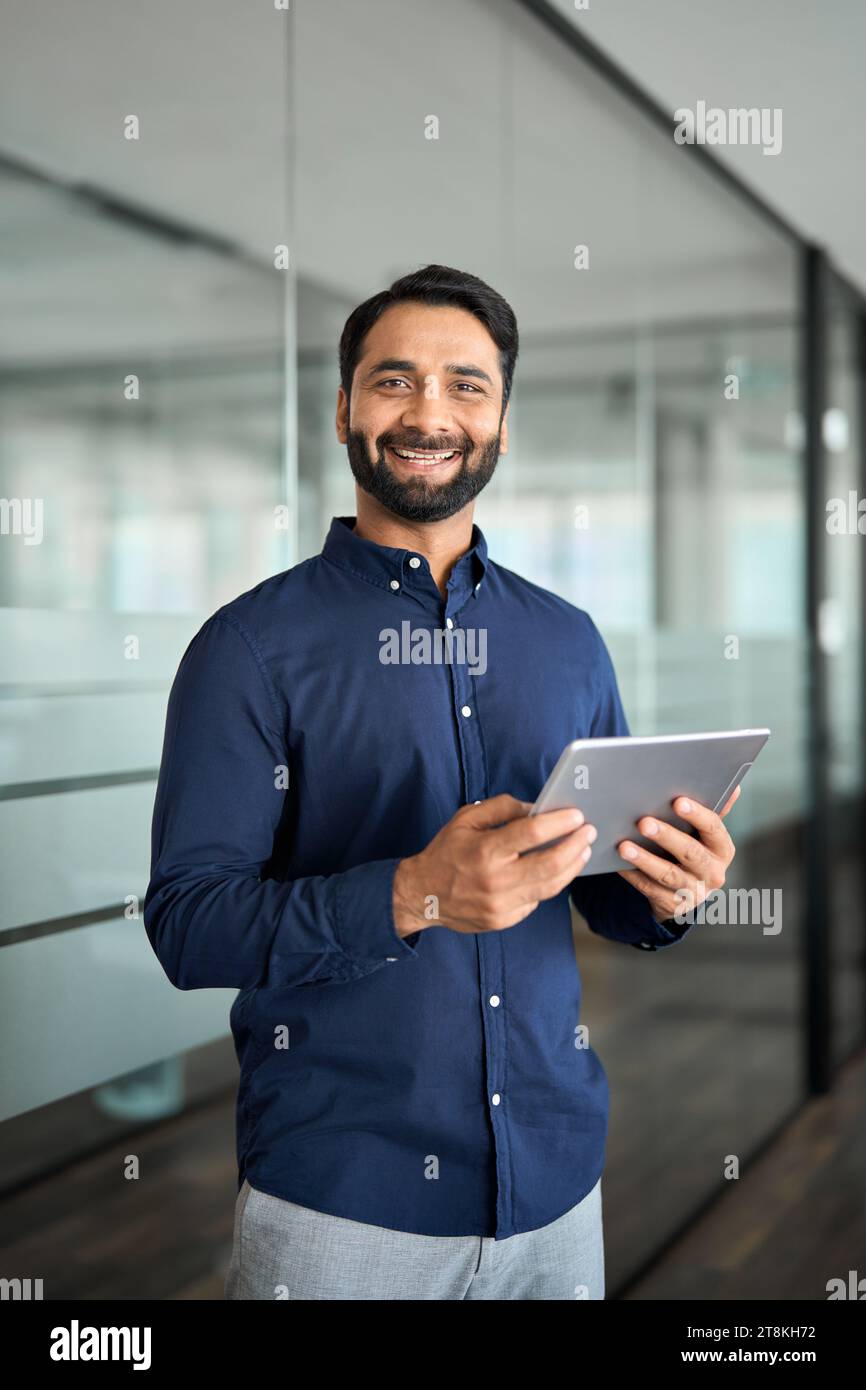 Happy Indian businessman using tab working standing in office. Vertical ...