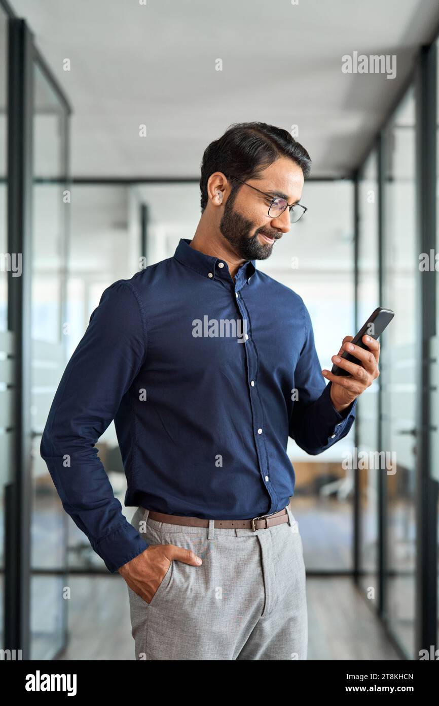 Indian business man employee using mobile phone standing in office ...