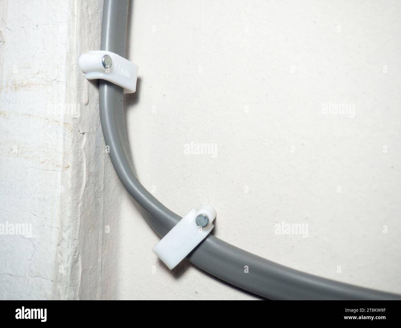 Fastening the wire to the wall. Ceiling mounting. Electric cord in the ...