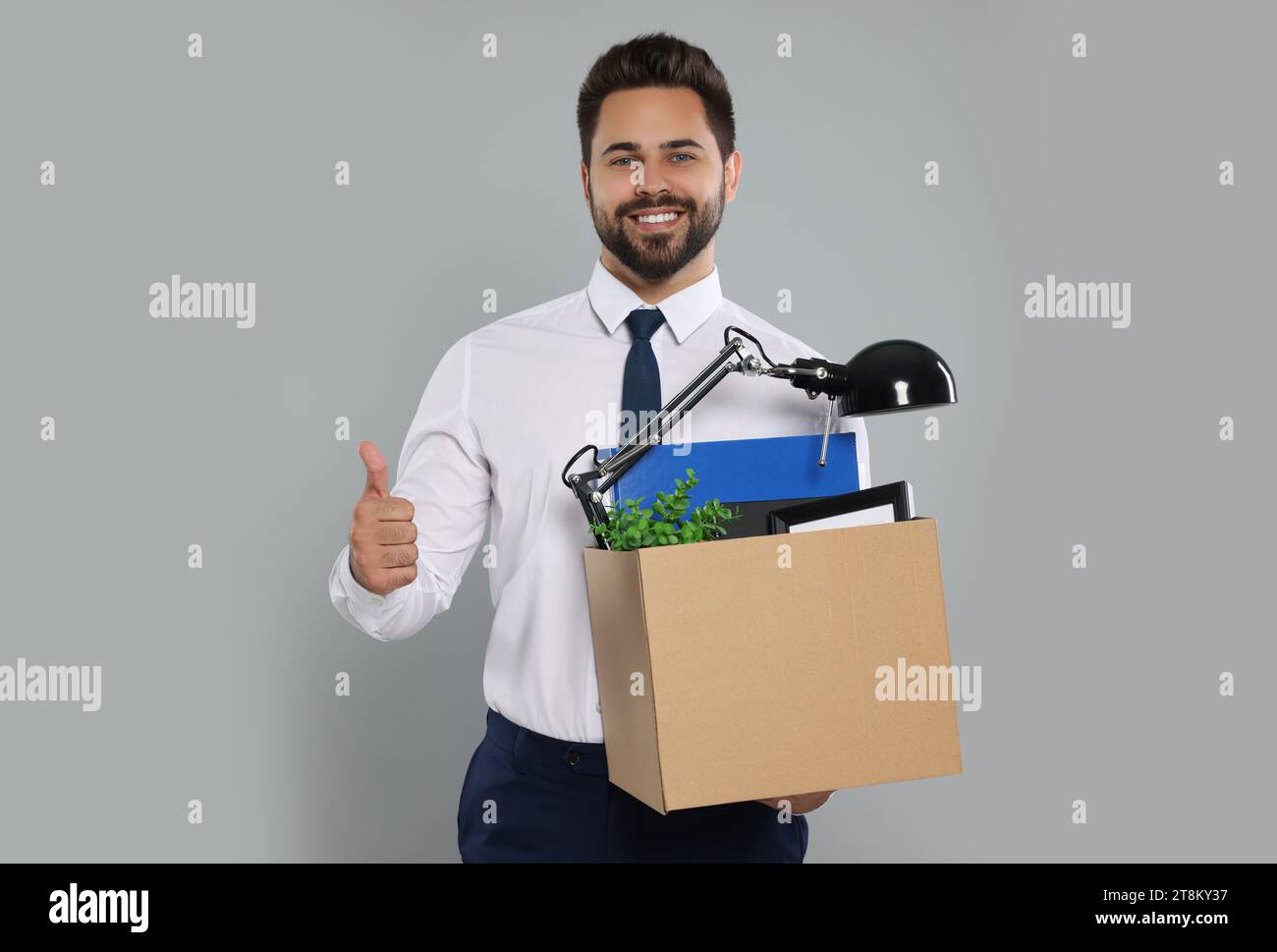 Happy unemployed man with box of personal office belongings showing ...