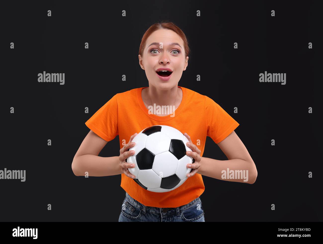 Emotional fan holding football ball on black background Stock Photo - Alamy