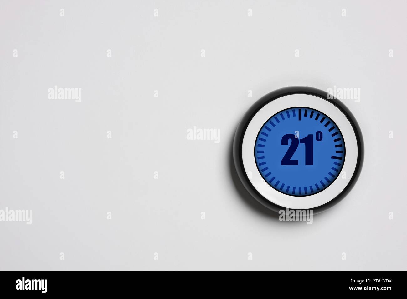 Thermostat displaying temperature in Celsius scale. Smart home device on white wall, space for ...
