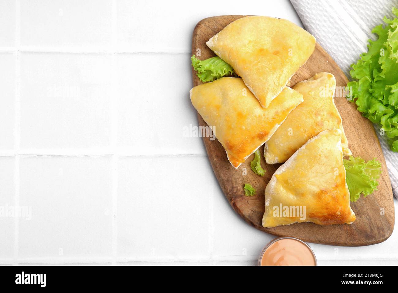 Delicious samosas with lettuce and sauce on white tiled table, flat lay ...