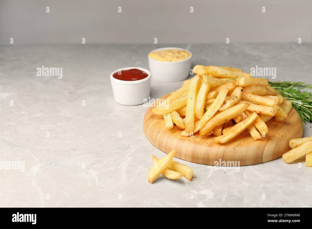 Delicious french fries served with sauces on light grey marble table ...