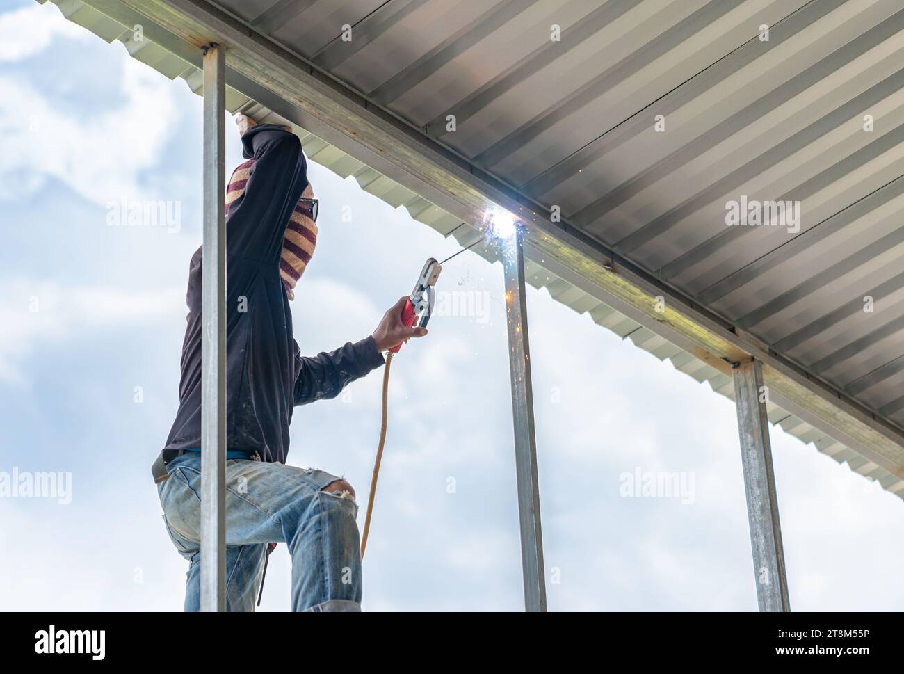 Workers at a construction site weld metal structures of roof in ...