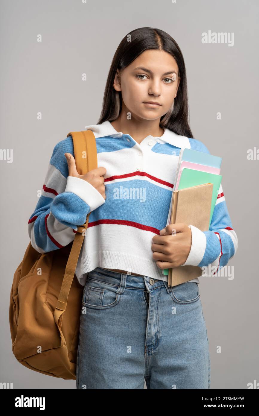 Teenage girl with backpack and notebooks. Serious unsmiling girl in ...