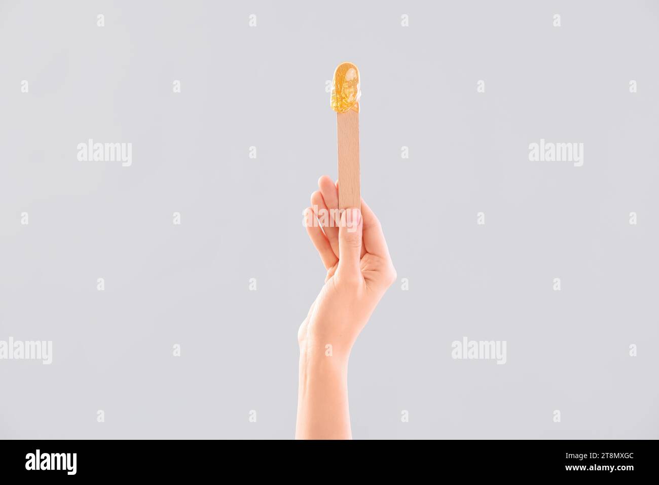 Hand holding spatula with sugaring paste on light background Stock ...