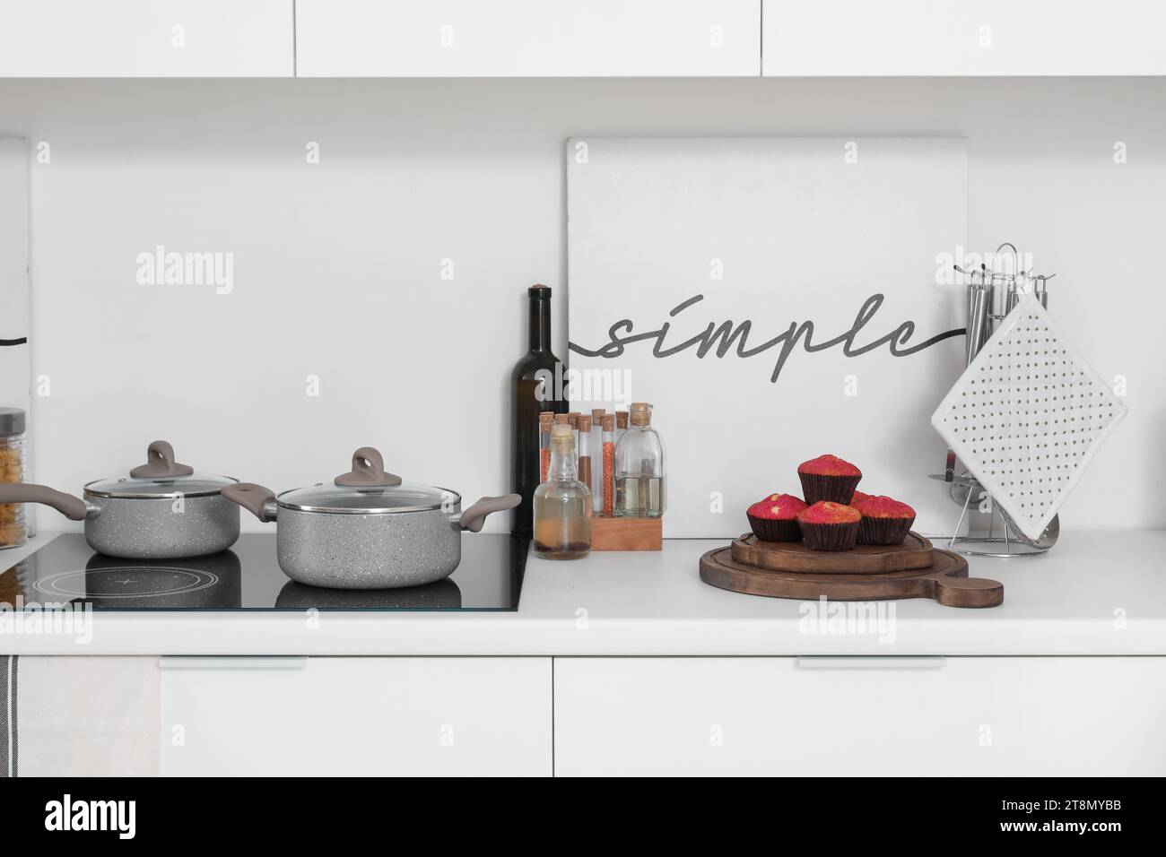 White kitchen counter with electric stove, cooking pots and fresh ...