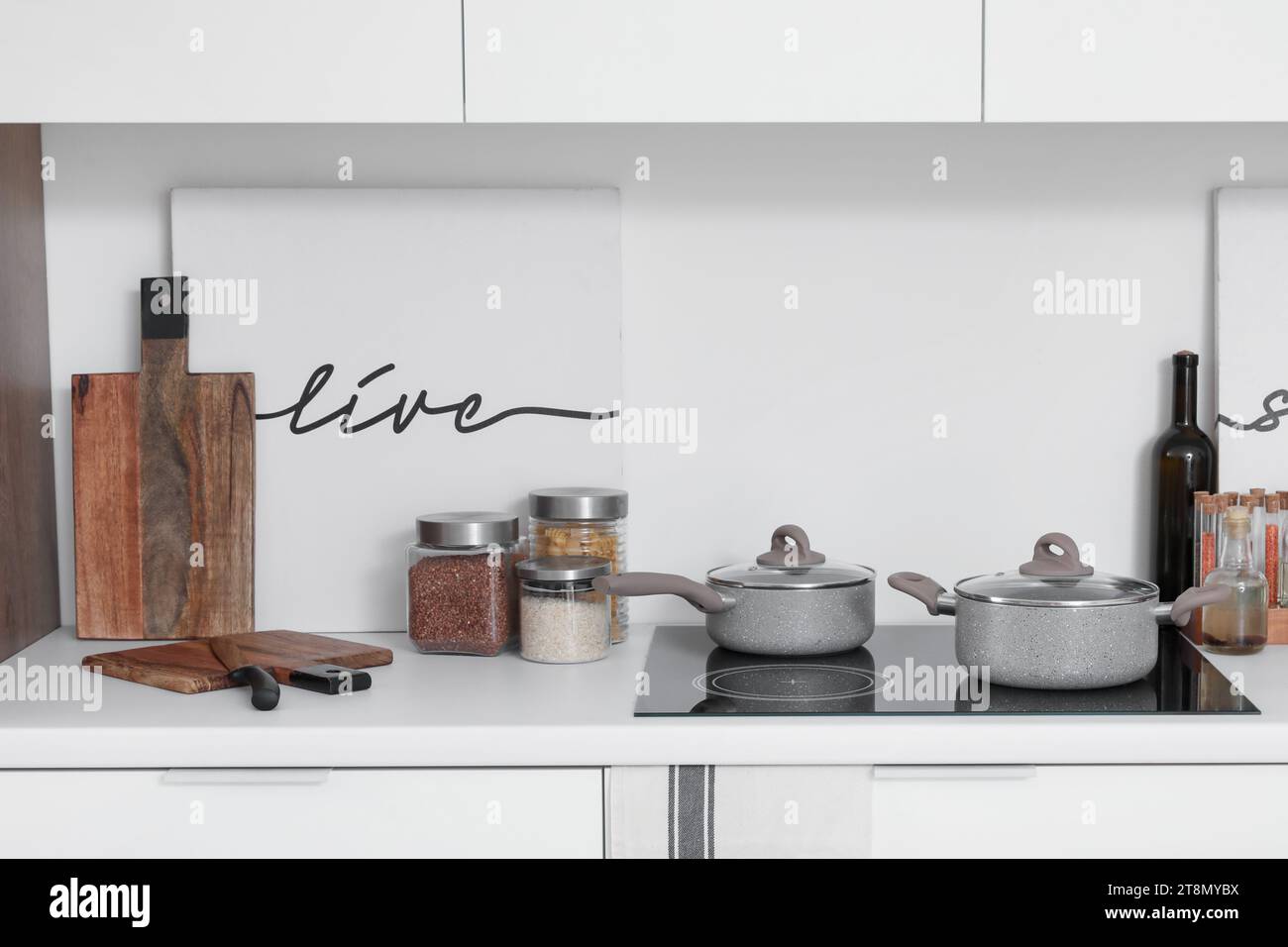 White kitchen counter with electric stove, cooking pots and utensils ...