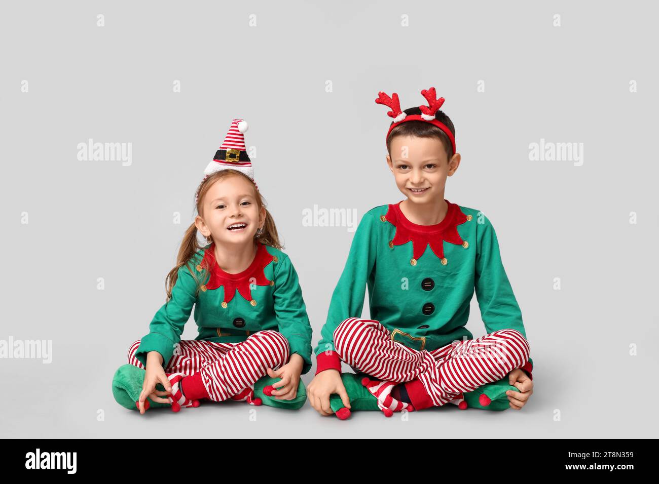 Cute little children dressed as elves on grey background Stock Photo ...