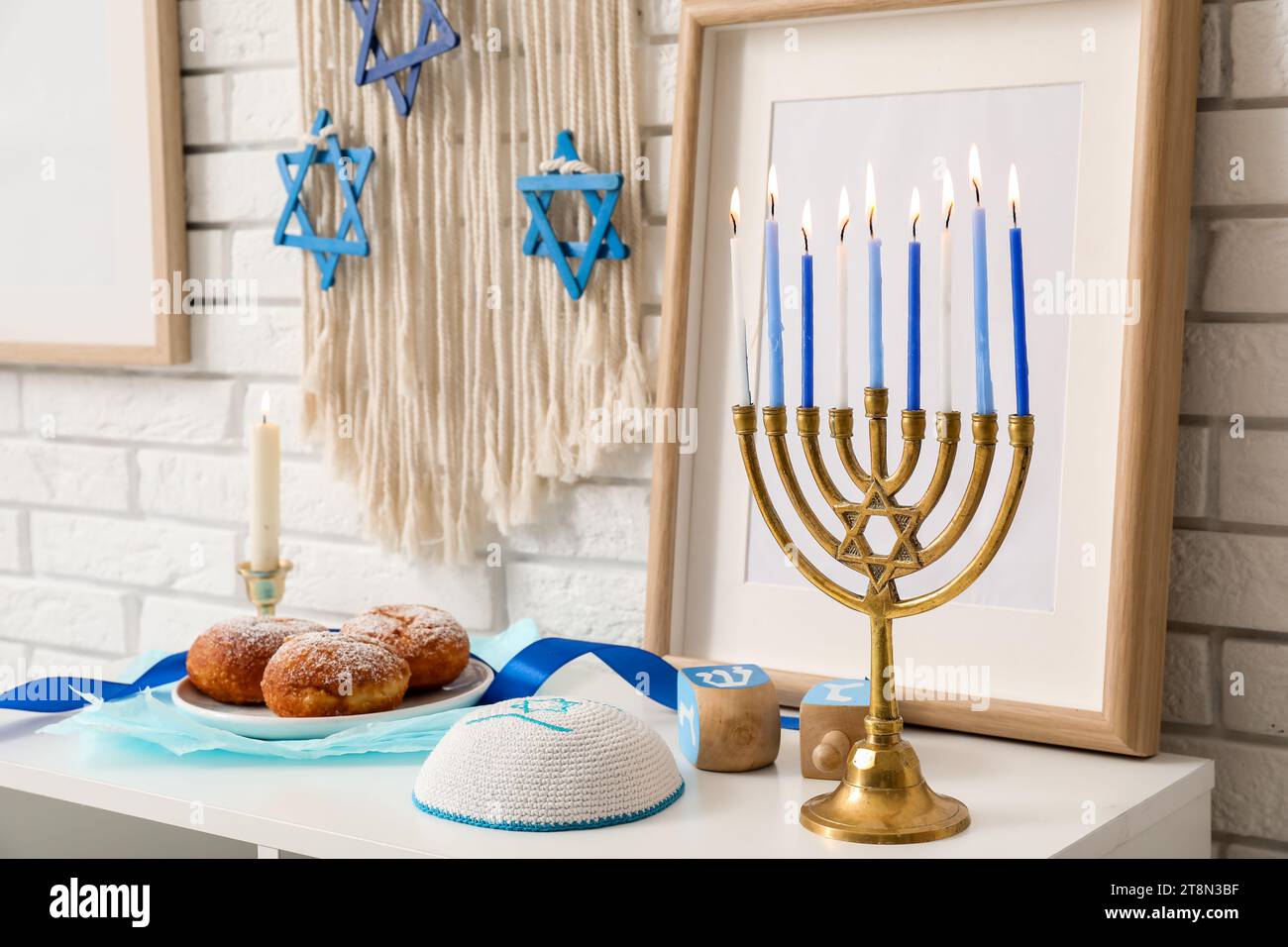 White table with menorah, kipa, sufganiyots and blank frame near white ...
