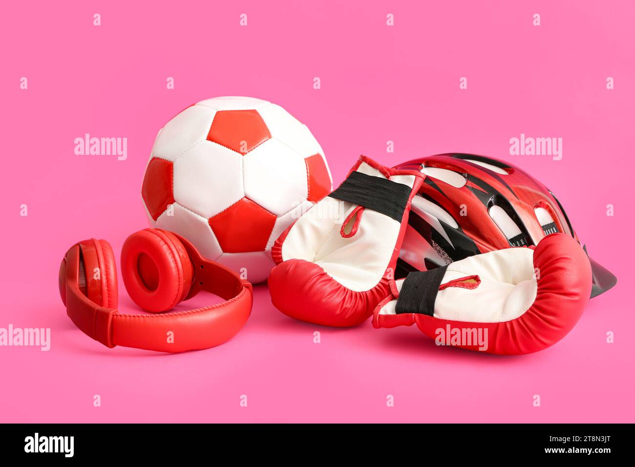 Soccer ball with boxing gloves, headphones and helmet on pink ...