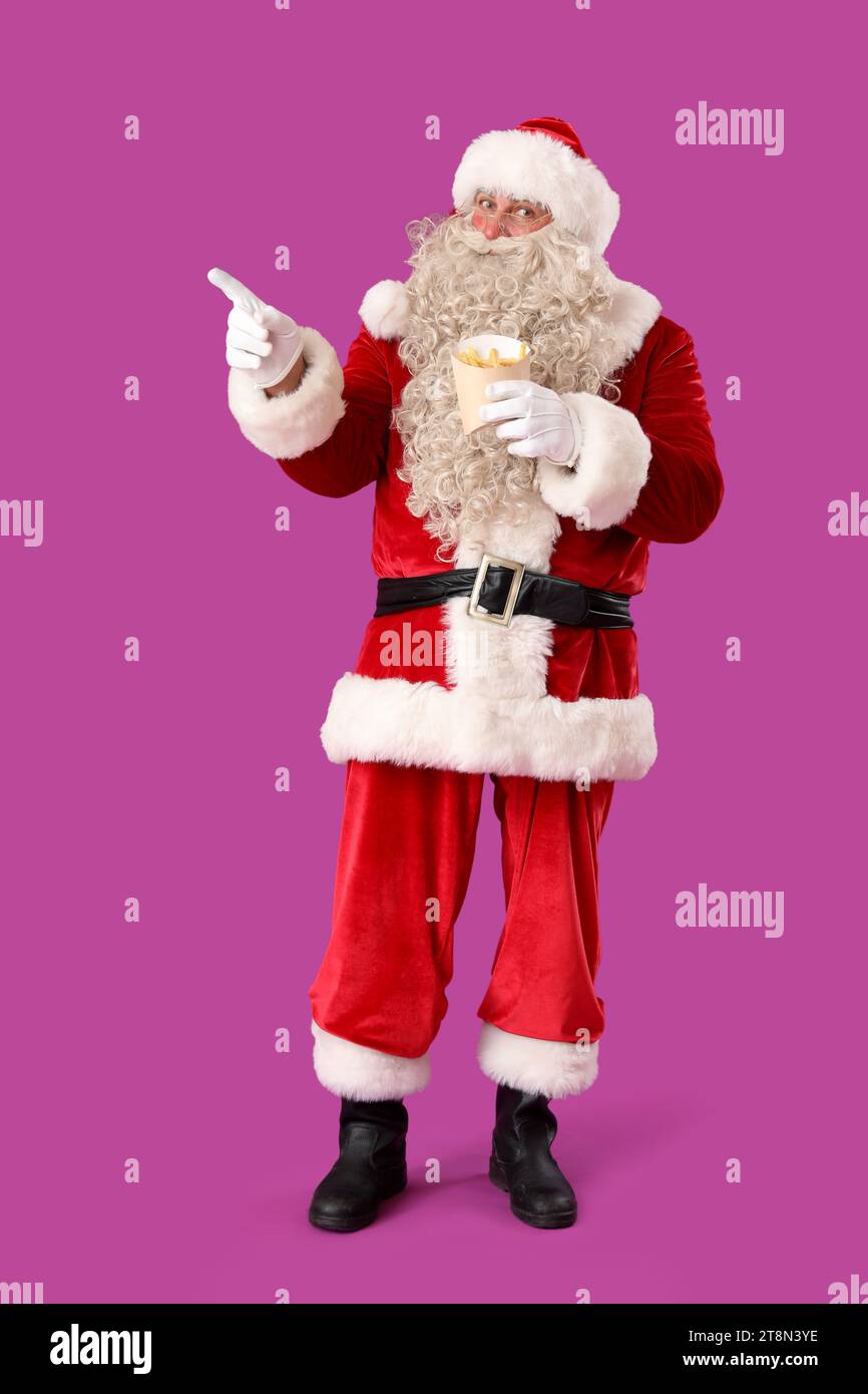 Santa Claus with tasty french fries pointing at something on purple ...