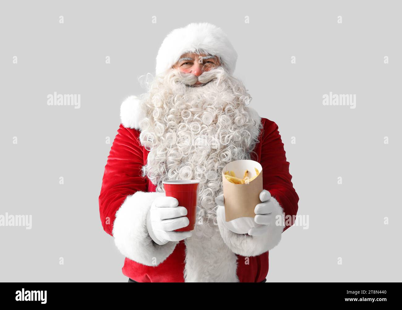 Santa Claus with cup of cola and tasty french fries on white background ...
