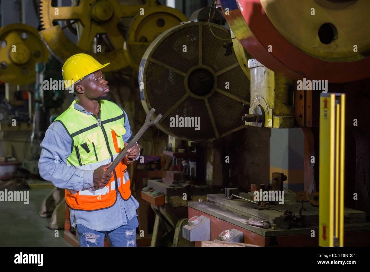 An individual in safety gear is in an industrial factory, holding a ...