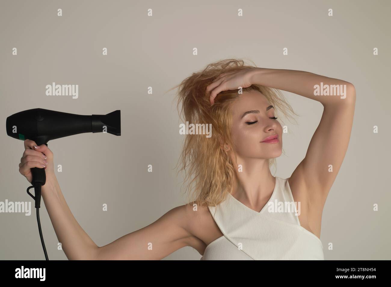 Beautiful woman drying her hair with a hairdryer isolated on studio ...