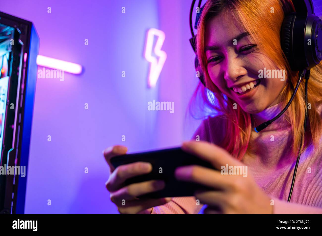 Happy Gamer playing video game online with smartphone with neon lights ...